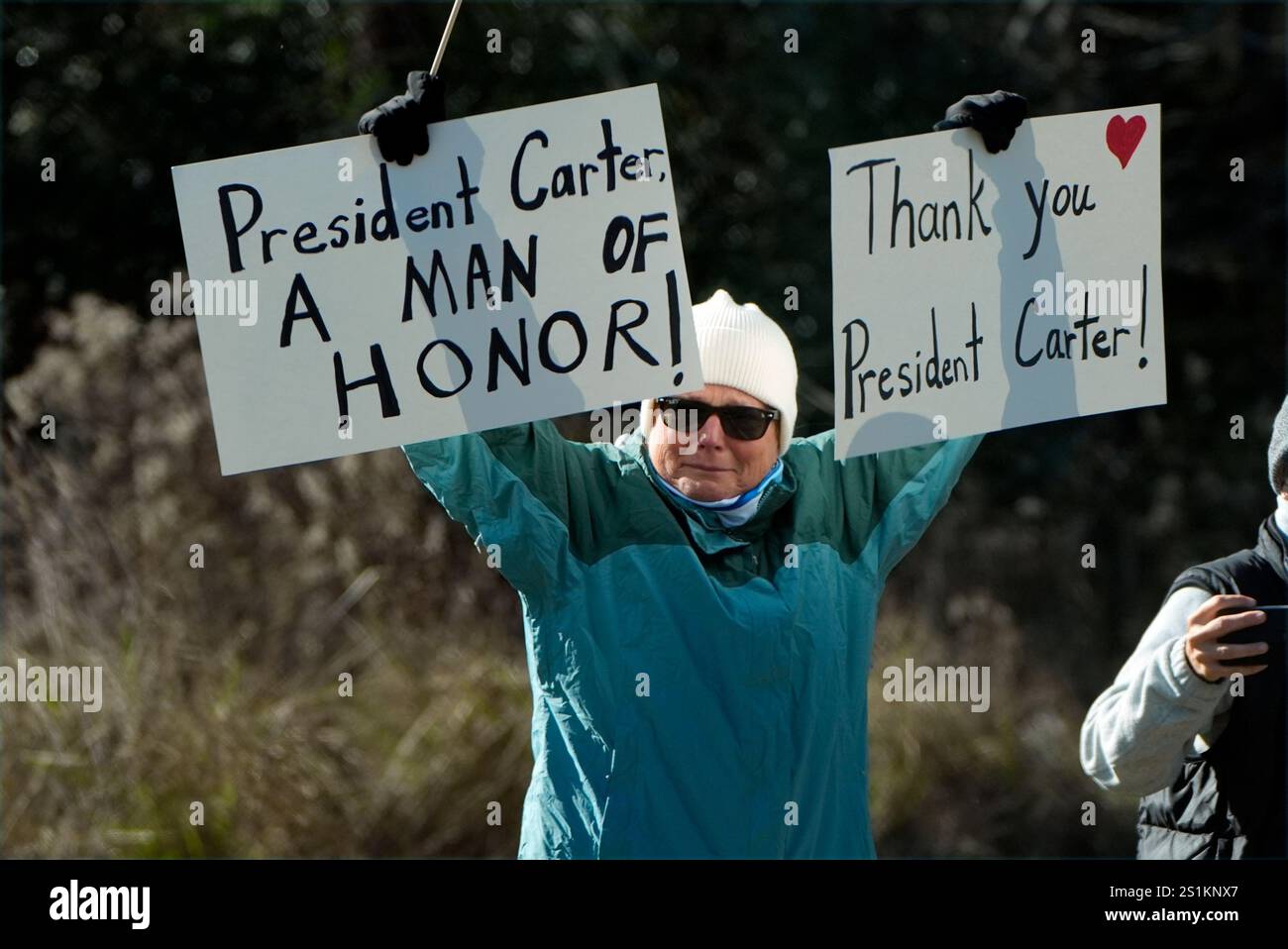 A person holds signs as the hearse containing the casket of former ...