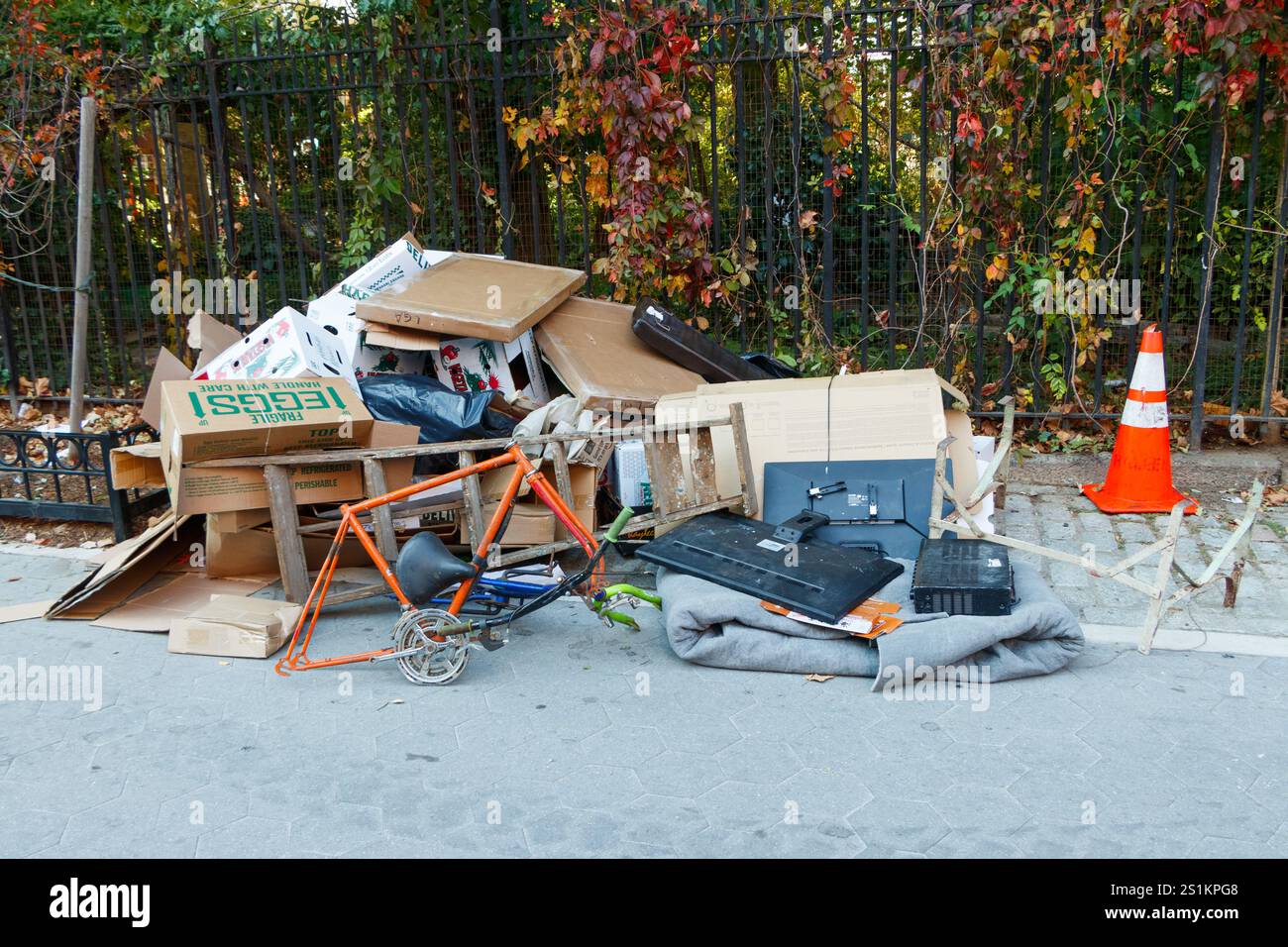 A pile of discarded items including a broken bicycle, cardboard boxes ...