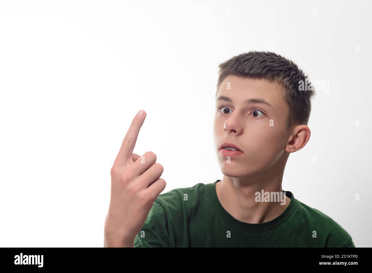 A young man with a shocked expression points to something off-camera ...