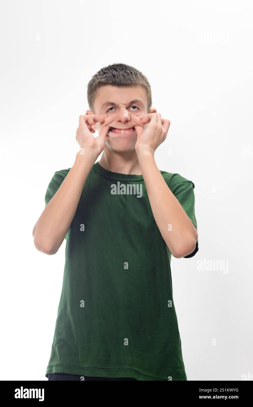 A photo of a teenage boy pulling his cheeks in a comical expression. He ...