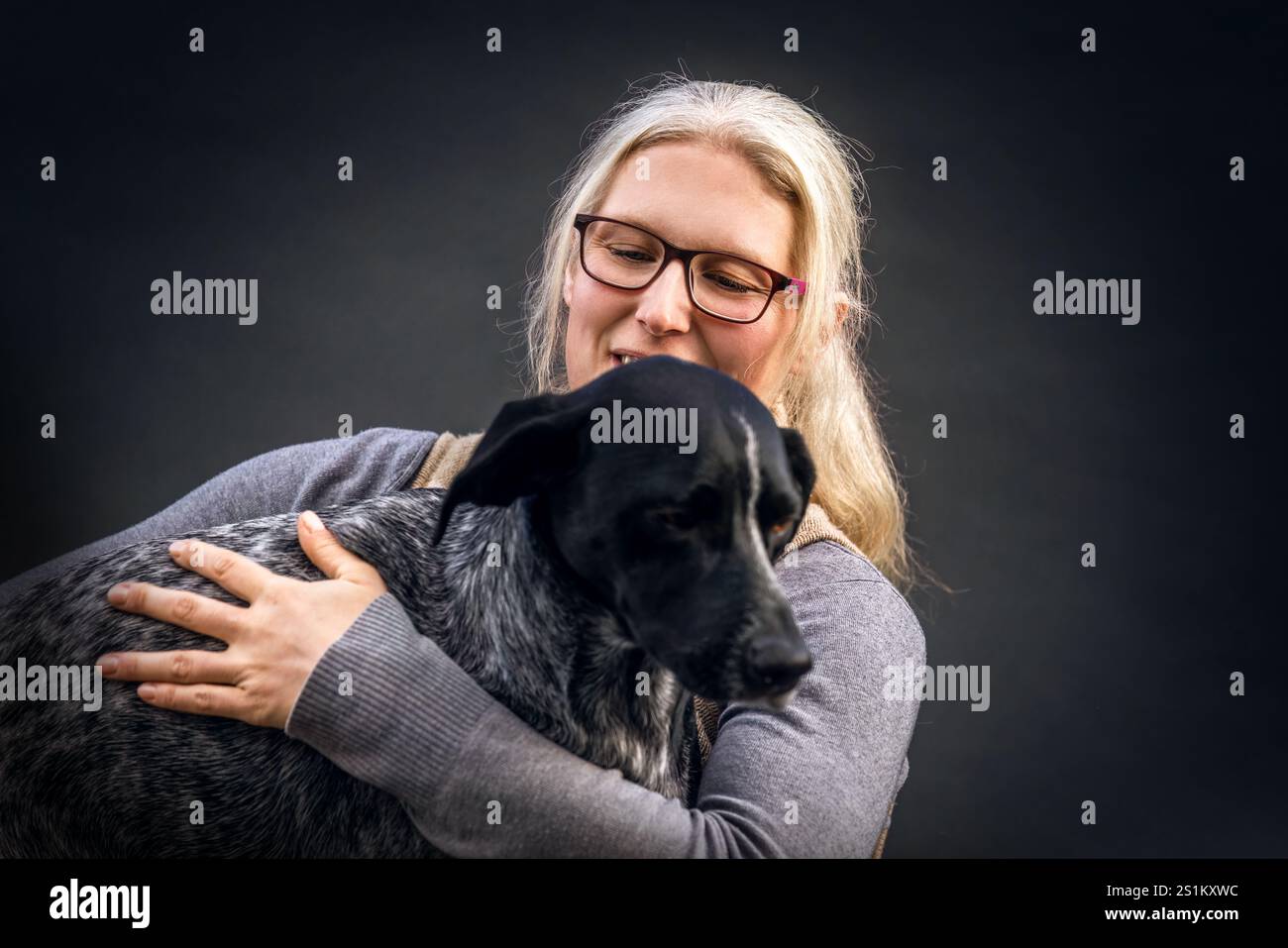 A woman cuddle with her dog in front of dark studio background Stock ...
