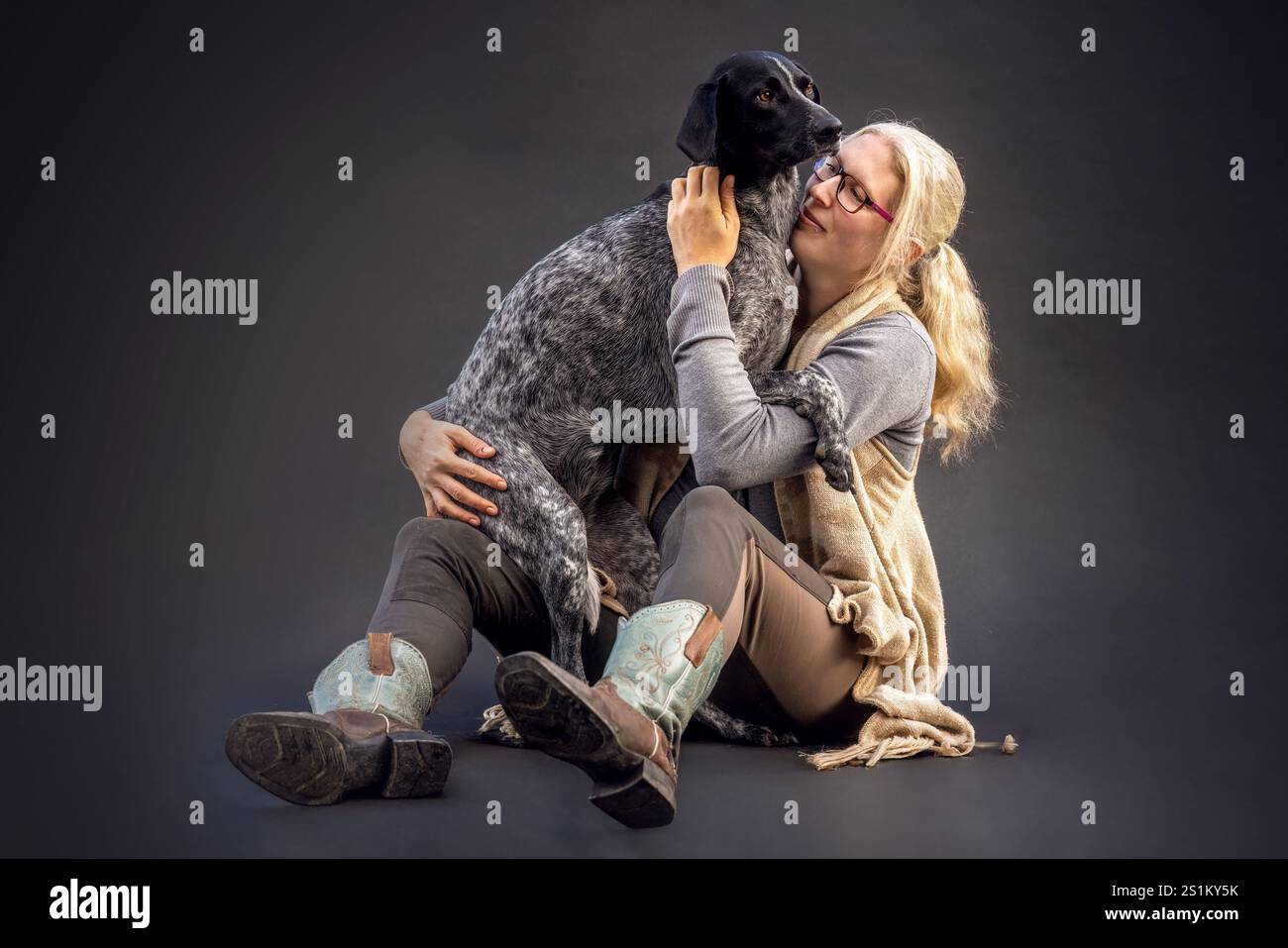 A woman cuddle with her dog in front of dark studio background Stock ...