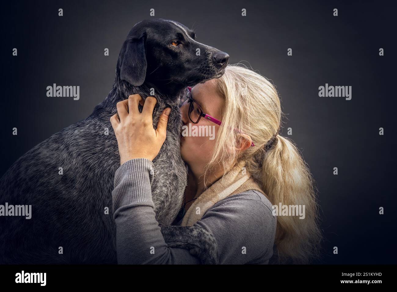 A woman cuddle with her dog in front of dark studio background Stock ...