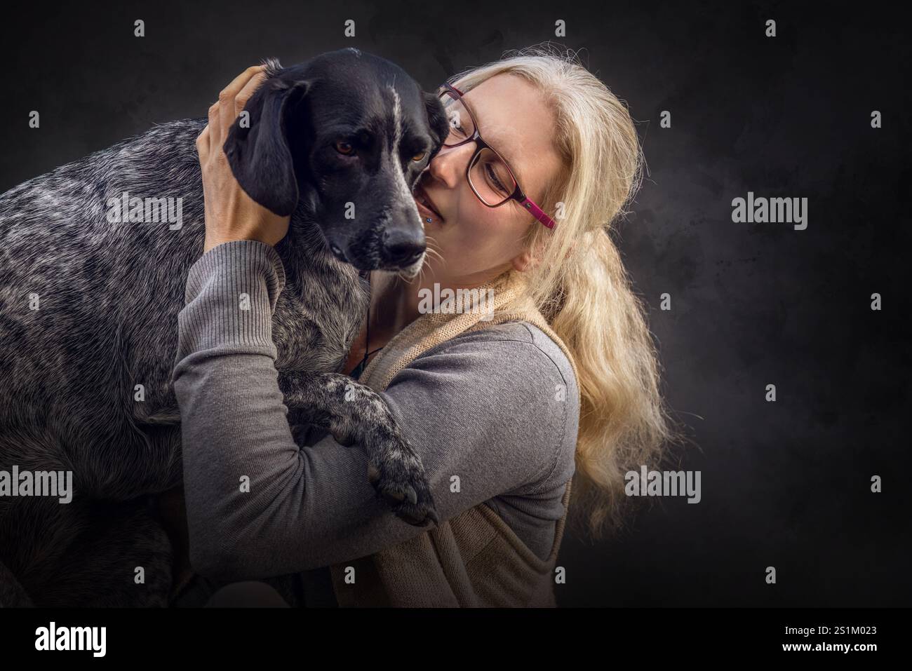 A woman cuddle with her dog in front of dark studio background Stock ...