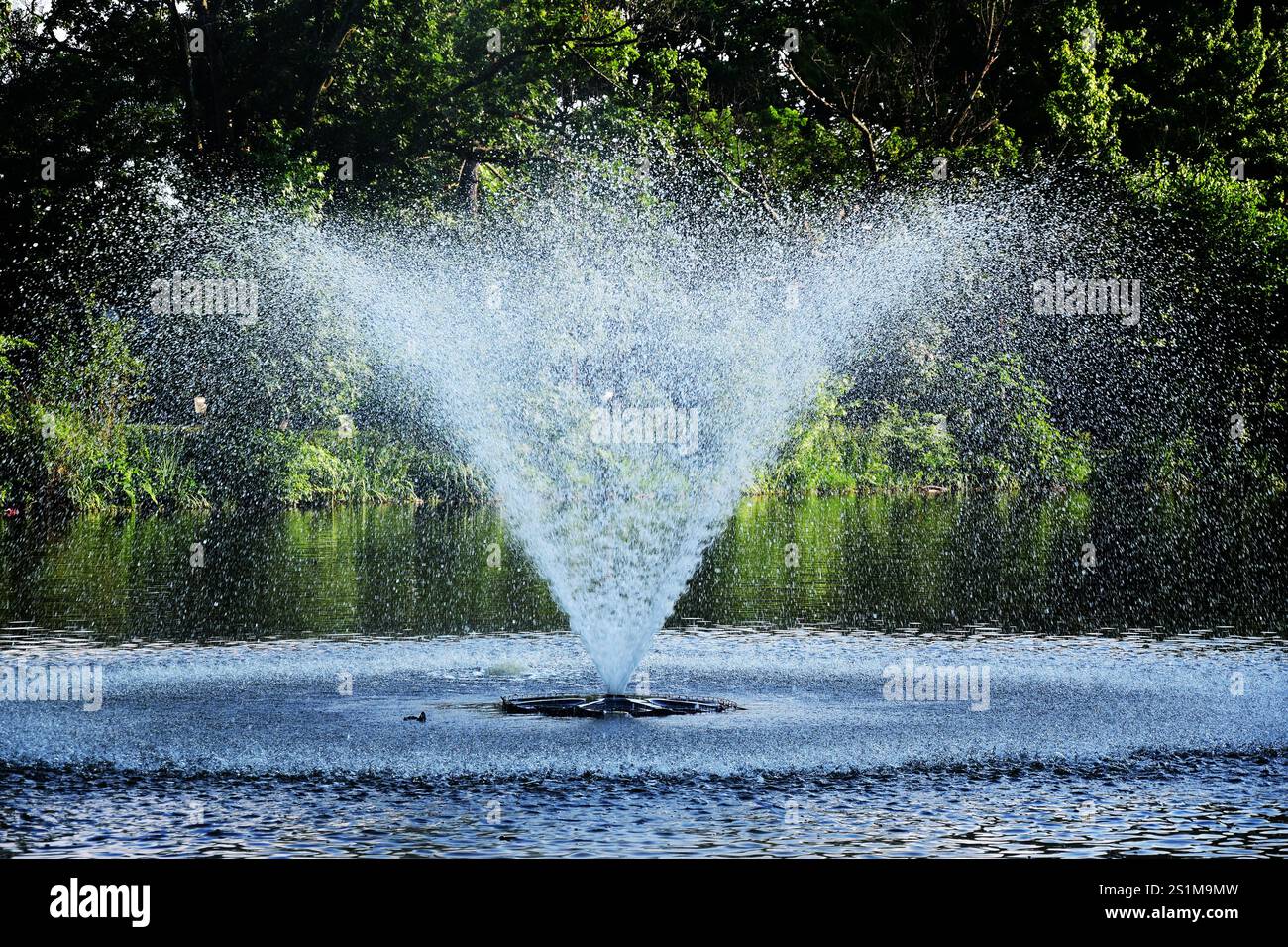 SUN SHOWER: A sprinkler system in the middle of a pond in Rahway park ...