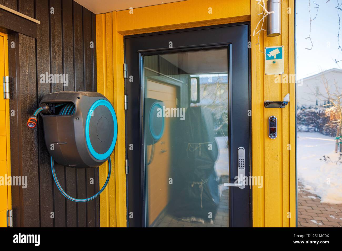 Close-up view of modern house entrance with yellow facade, glass door ...