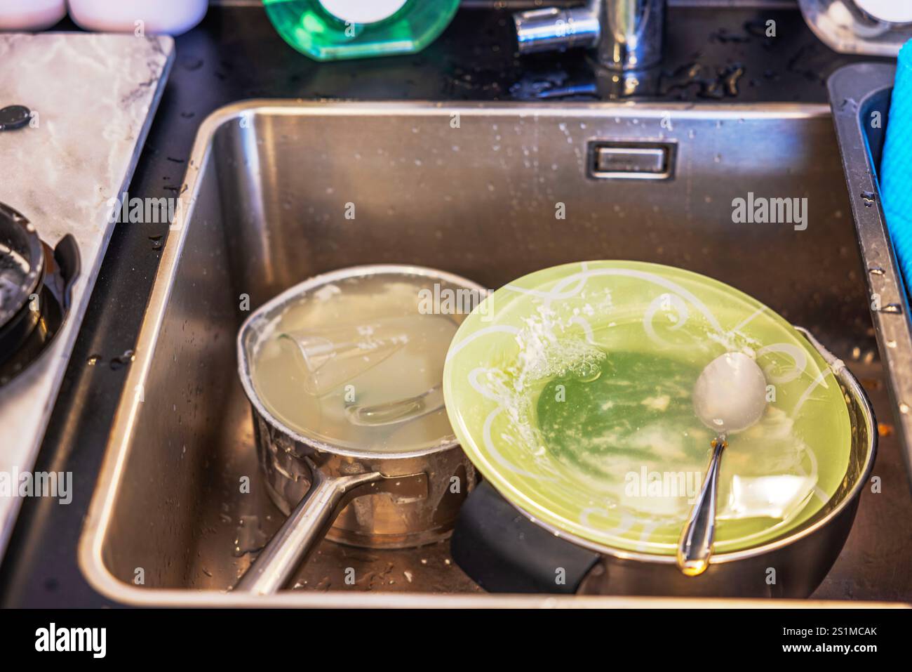 Dirty dishes in stainless steel kitchen sink with leftover food and ...