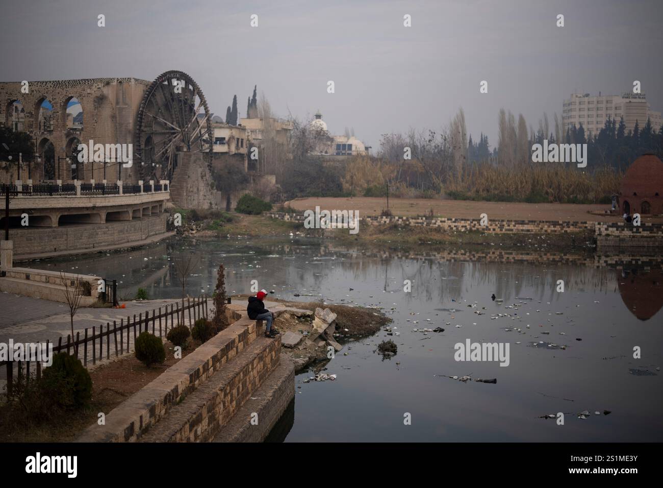 People sit near of one of the city's waterwheels known as "Norias of ...