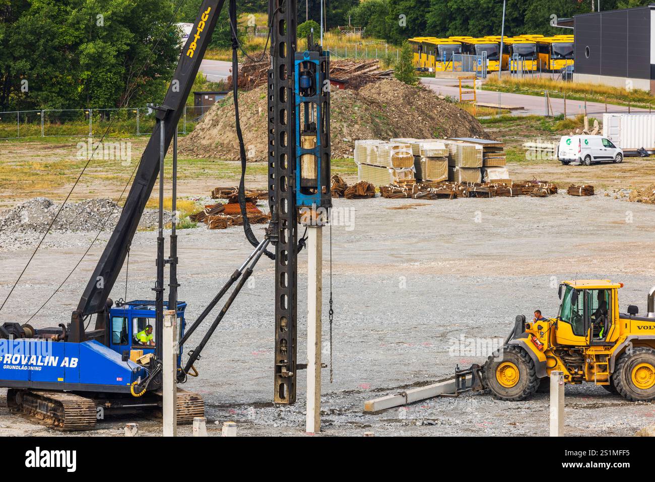 Construction site with heavy machinery operating on foundation piling ...