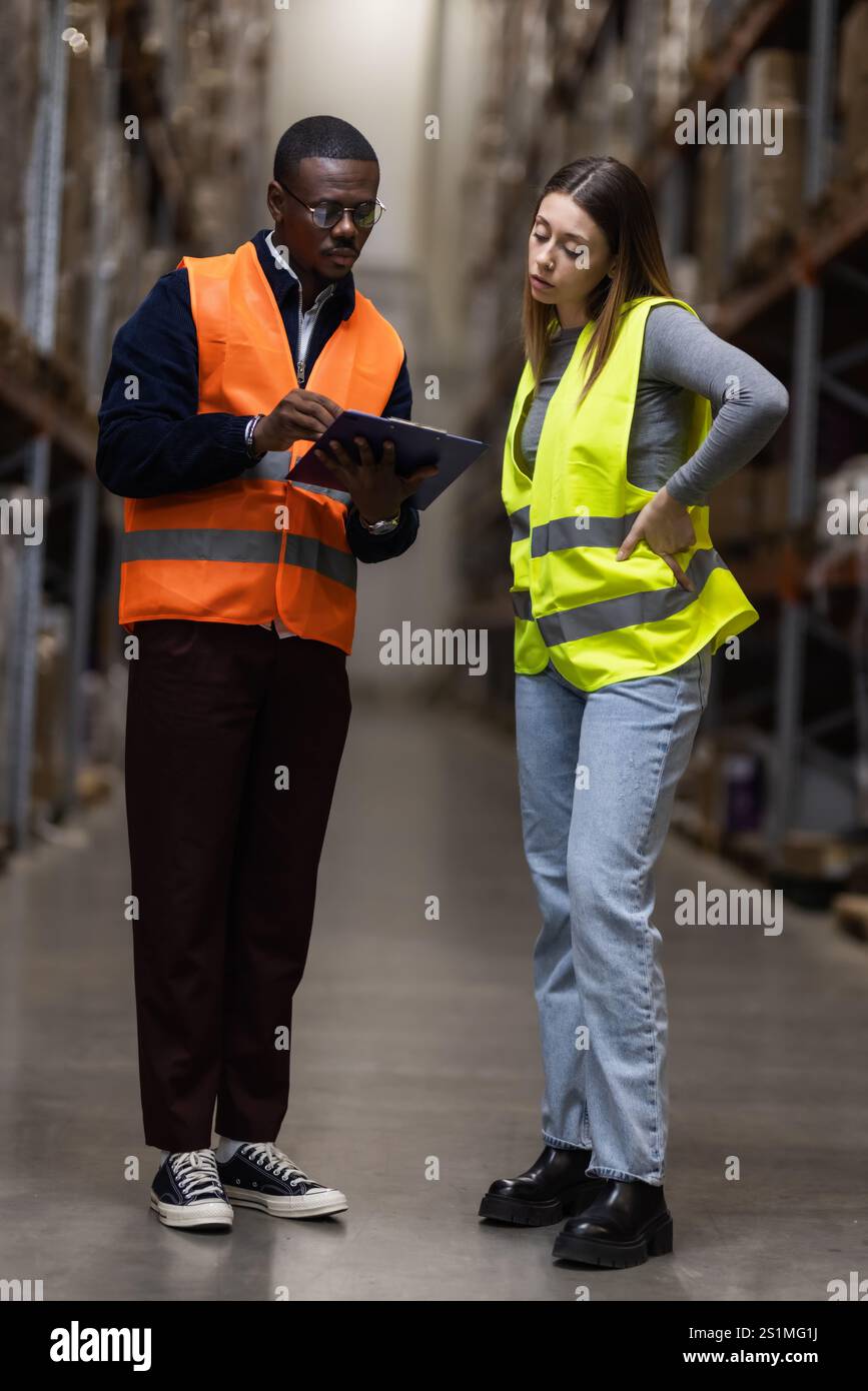Warehouse employees collaborate using a tablet to check inventory ...
