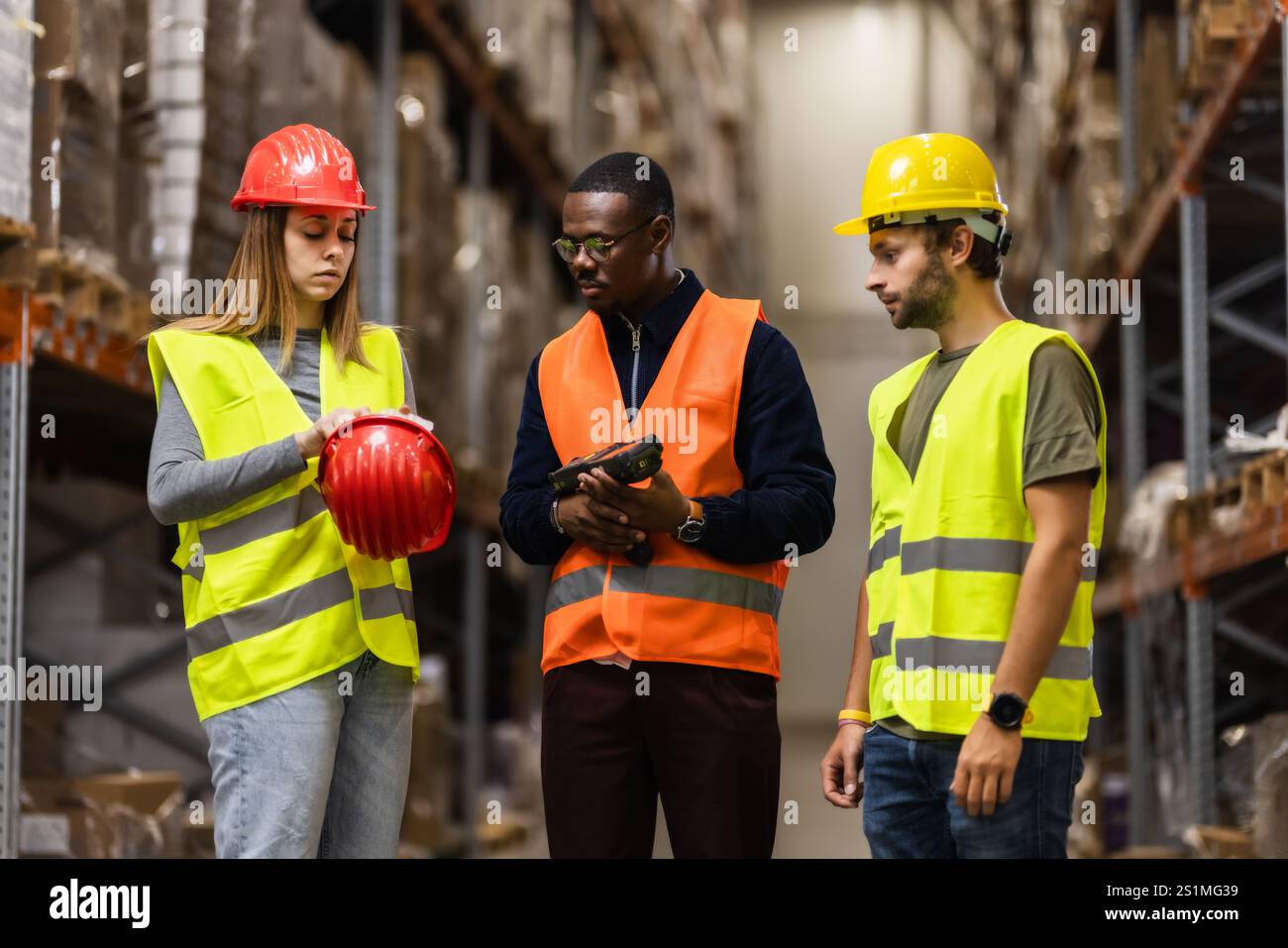 A team of warehouse employees discusses safety procedures while wearing ...