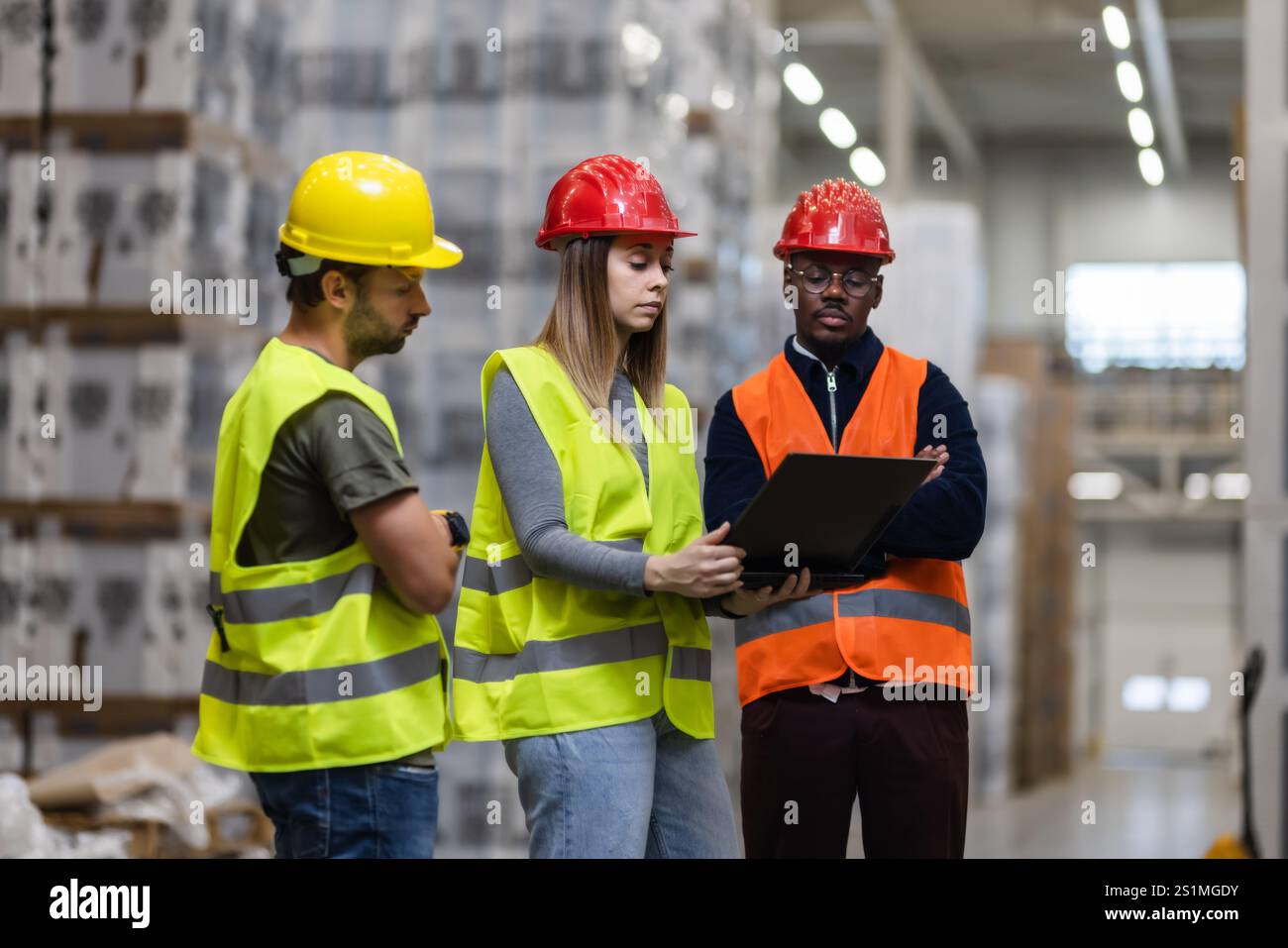 A diverse team of warehouse workers in safety gear reviews logistics ...