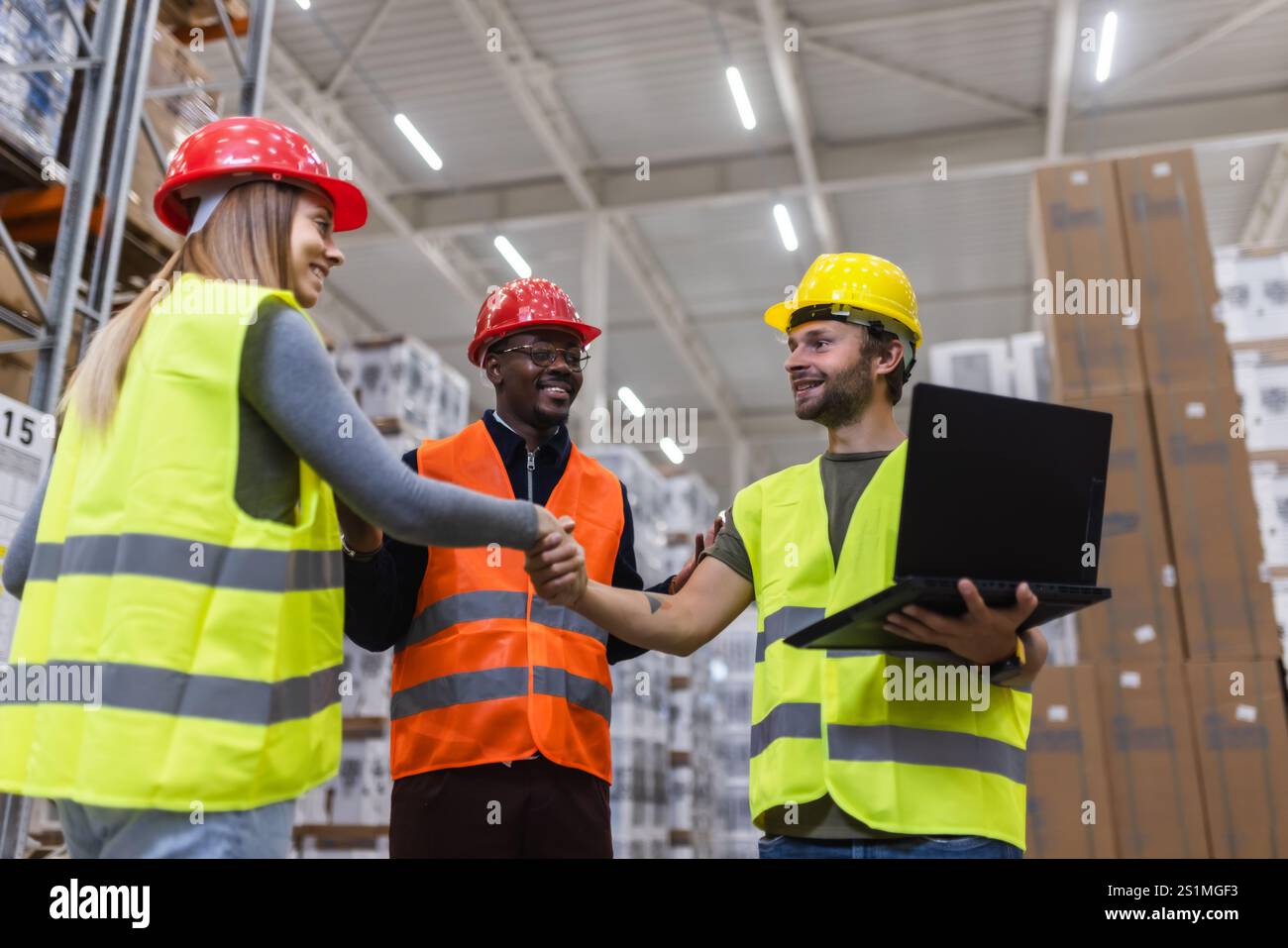 Three workers wearing safety vests and helmets are collaborating and ...