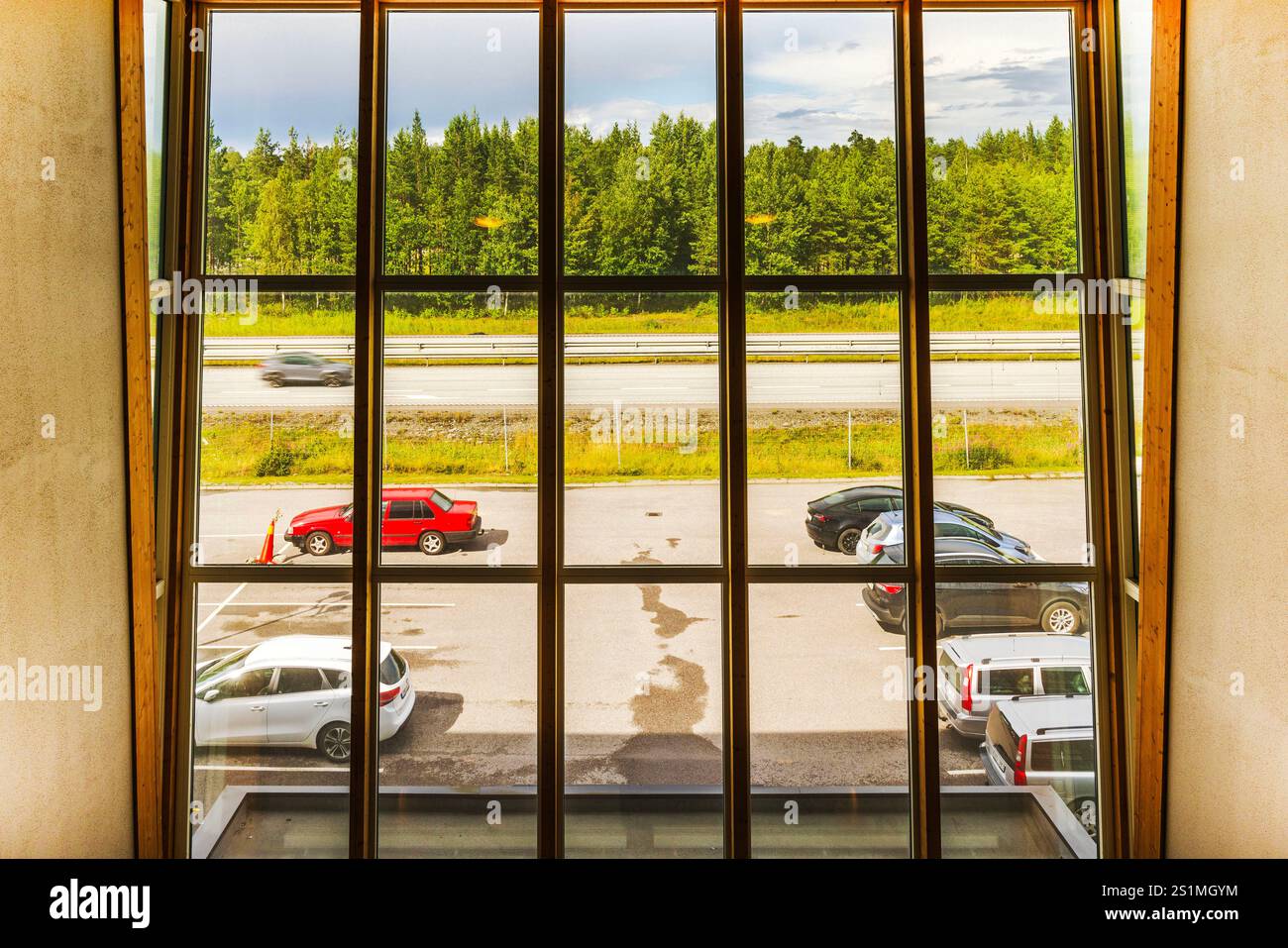 Large panoramic window view showing highway with cars, parking lot and ...