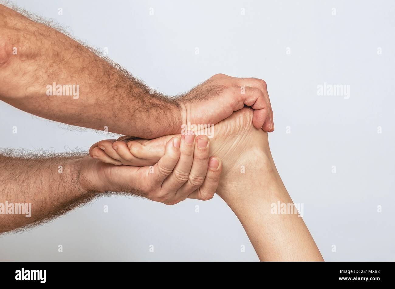 Male strong hairy hands embrace female toes and heel. Male hands do ...