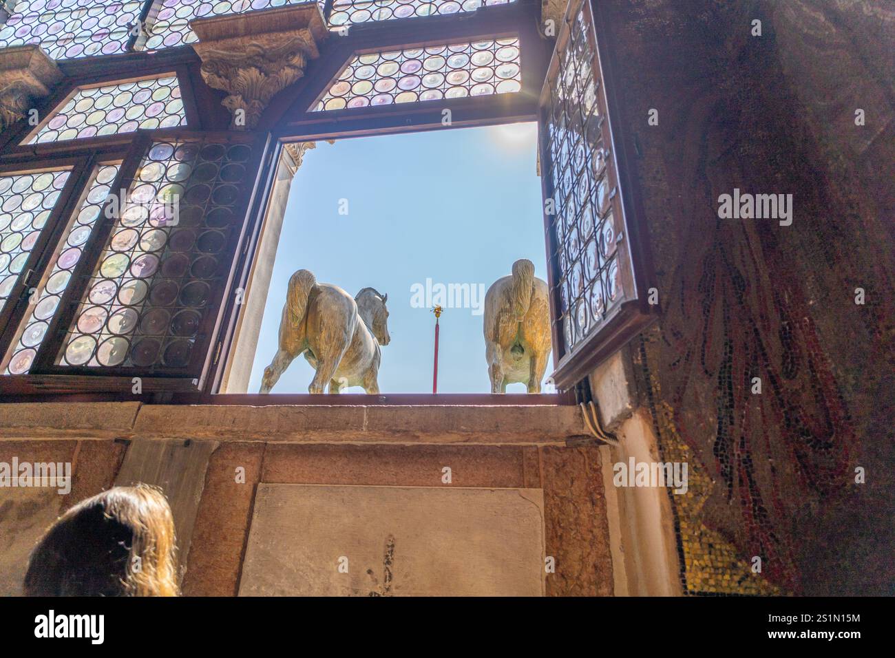 View of bronze horse statues through an ornate glass window with ...