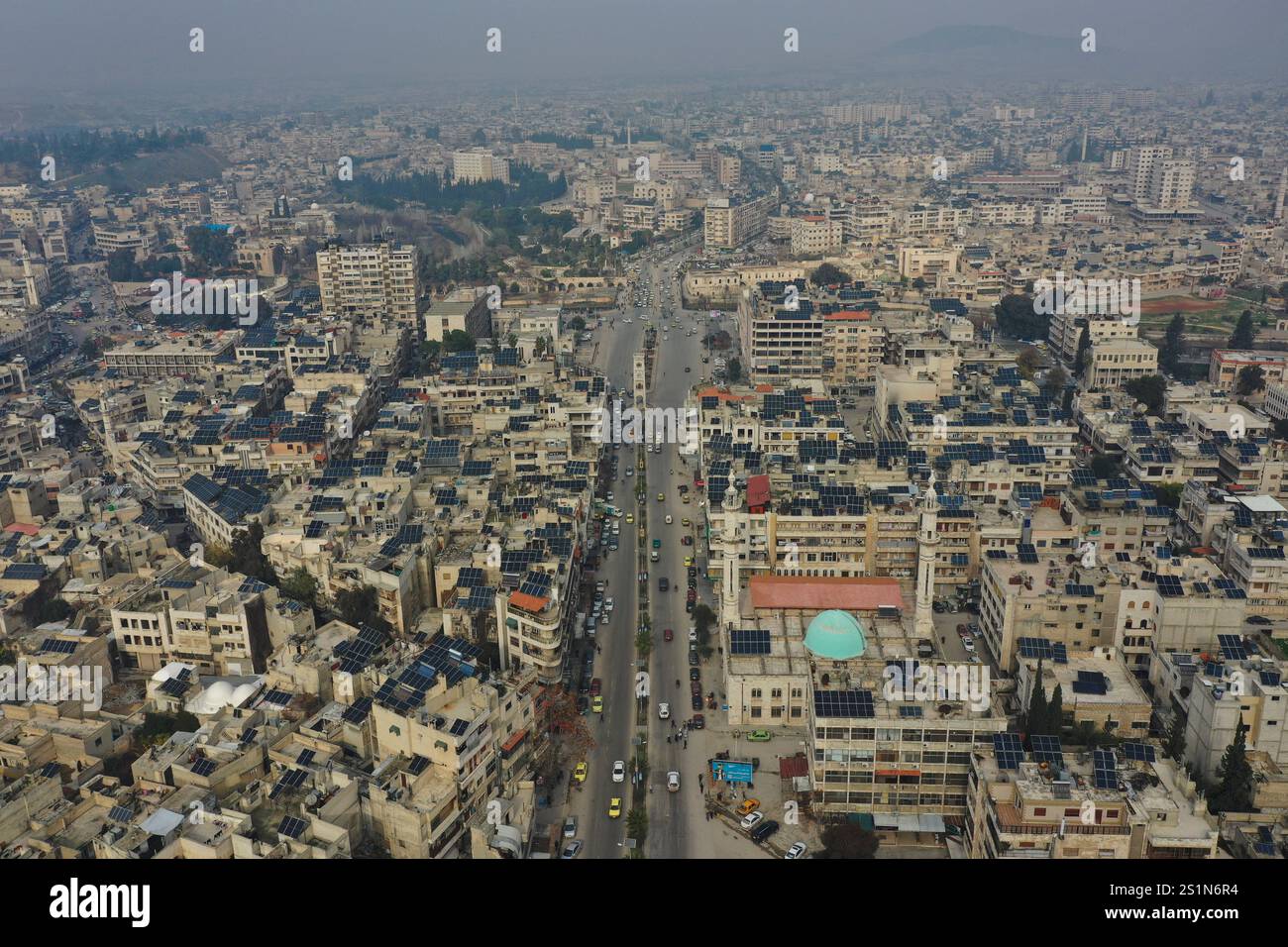 Cars drive along an avenue that leads to the Hama Clock Tower at the ...