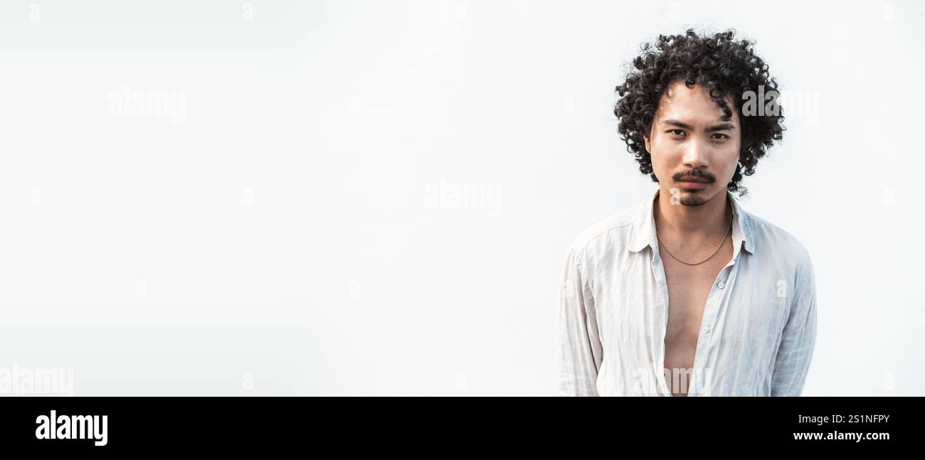 A young man with curly hair and a mustache wearing a light open ...