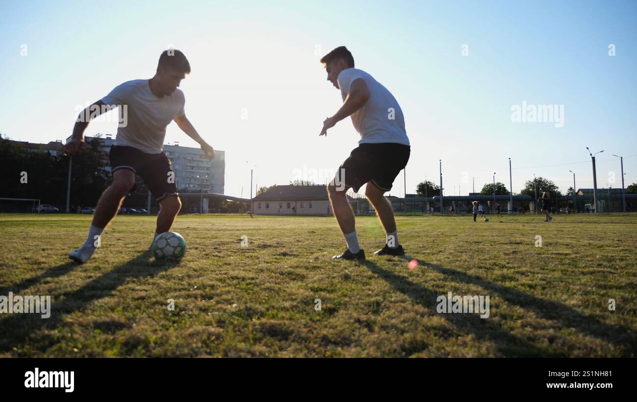Two sportsmen playing in soccer in stadium at sunset. Professional ...