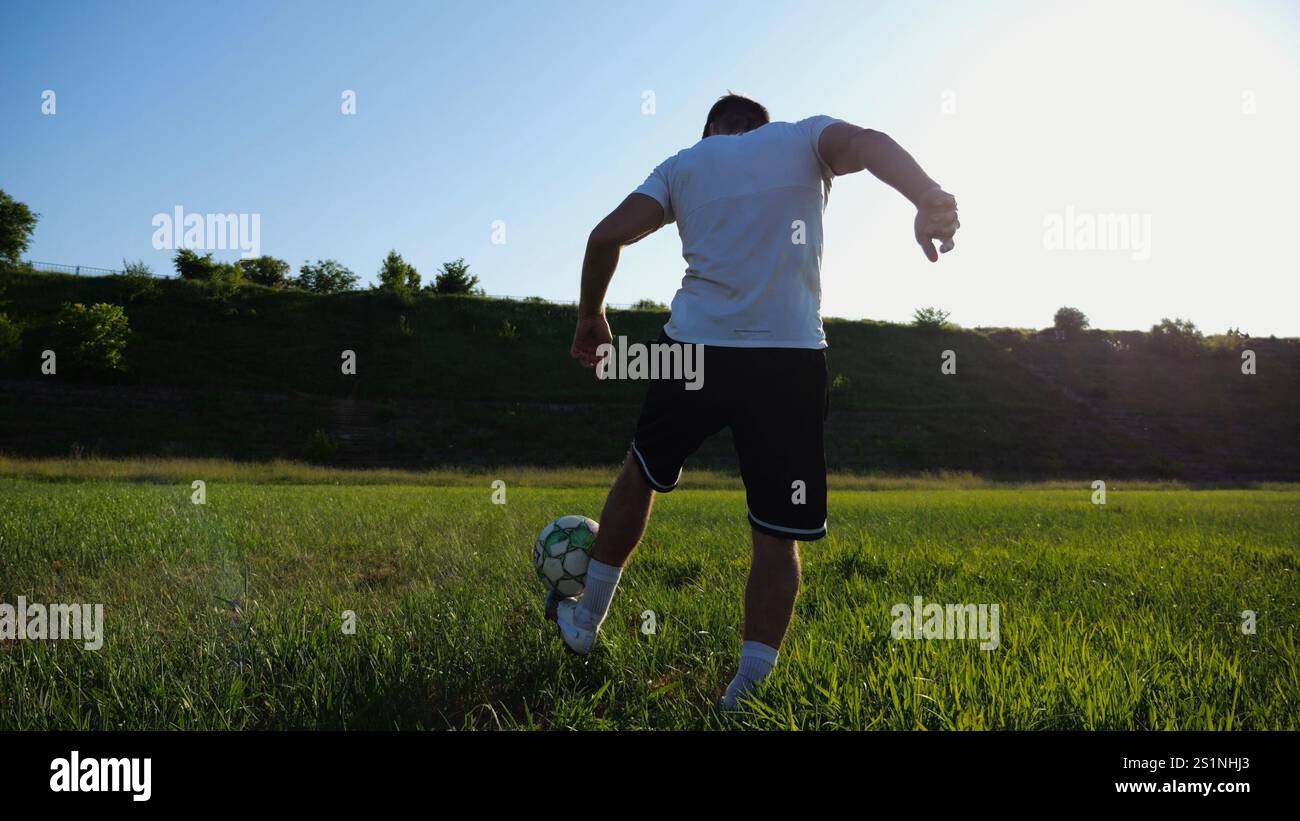 Sportsman juggling soccer ball on stadium at sunny day. Young man ...