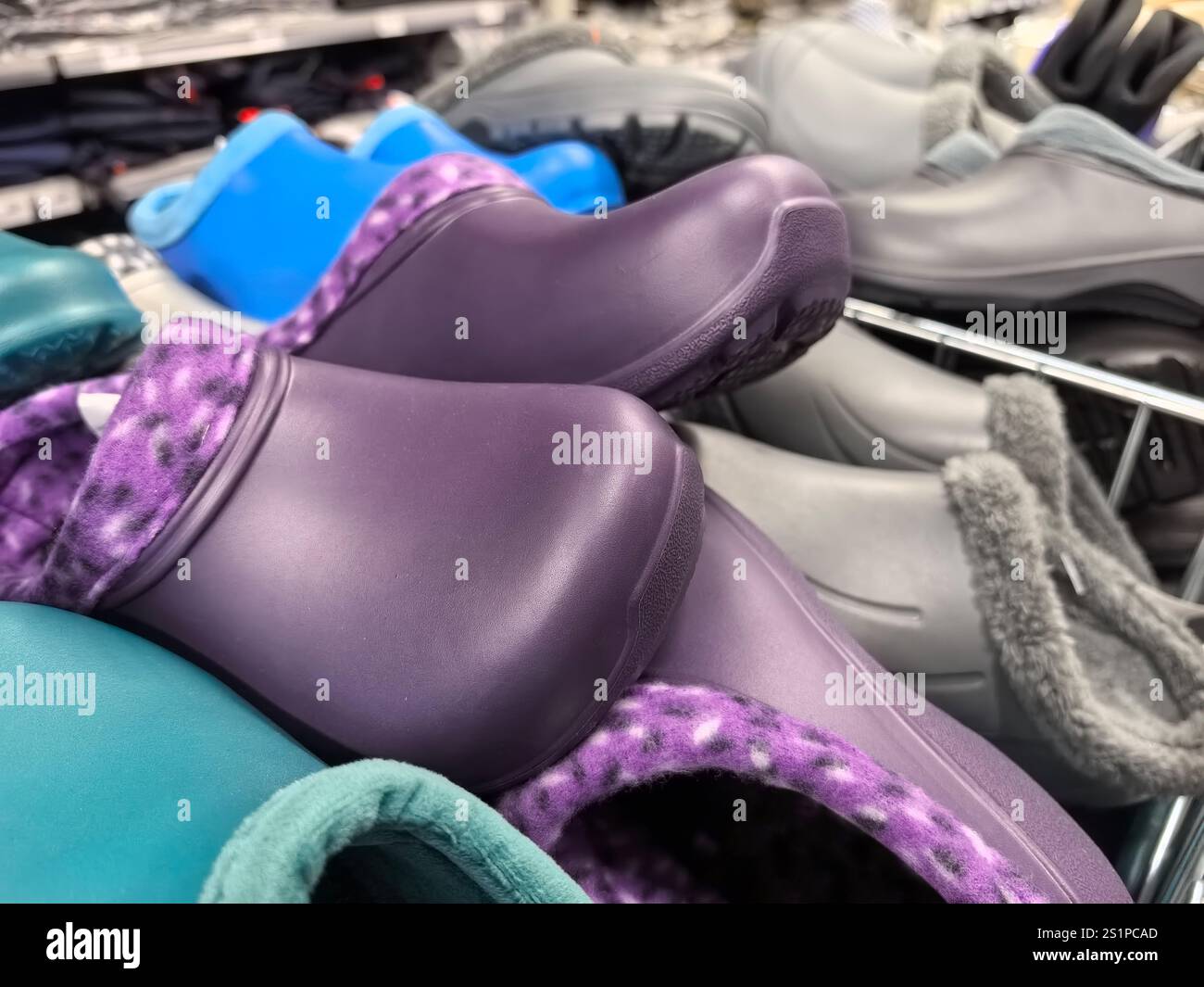 A collection of vibrant clogs rests neatly on display in a retail aisle ...