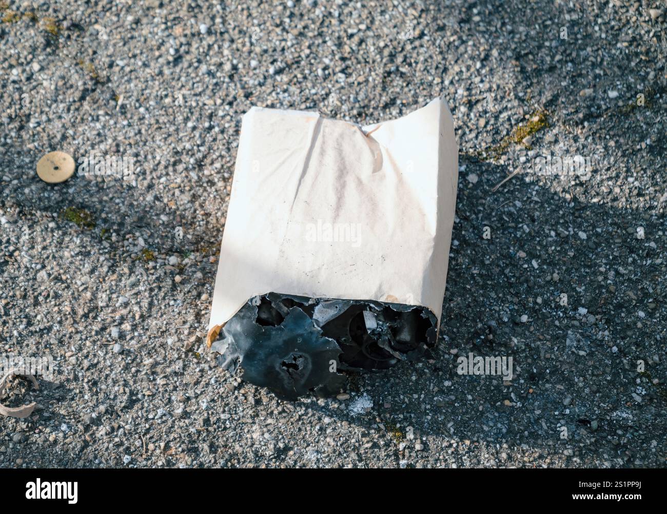 A partially melted and burned firework shell lying on the pavement in ...