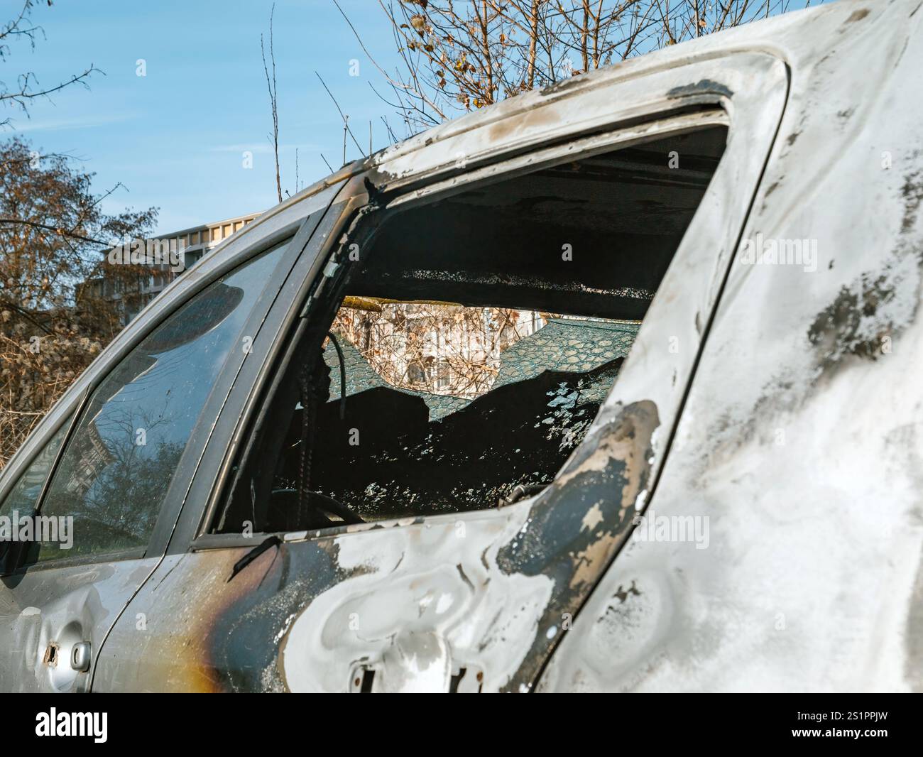 a burned car with shattered windows and fire damage in a parking area ...