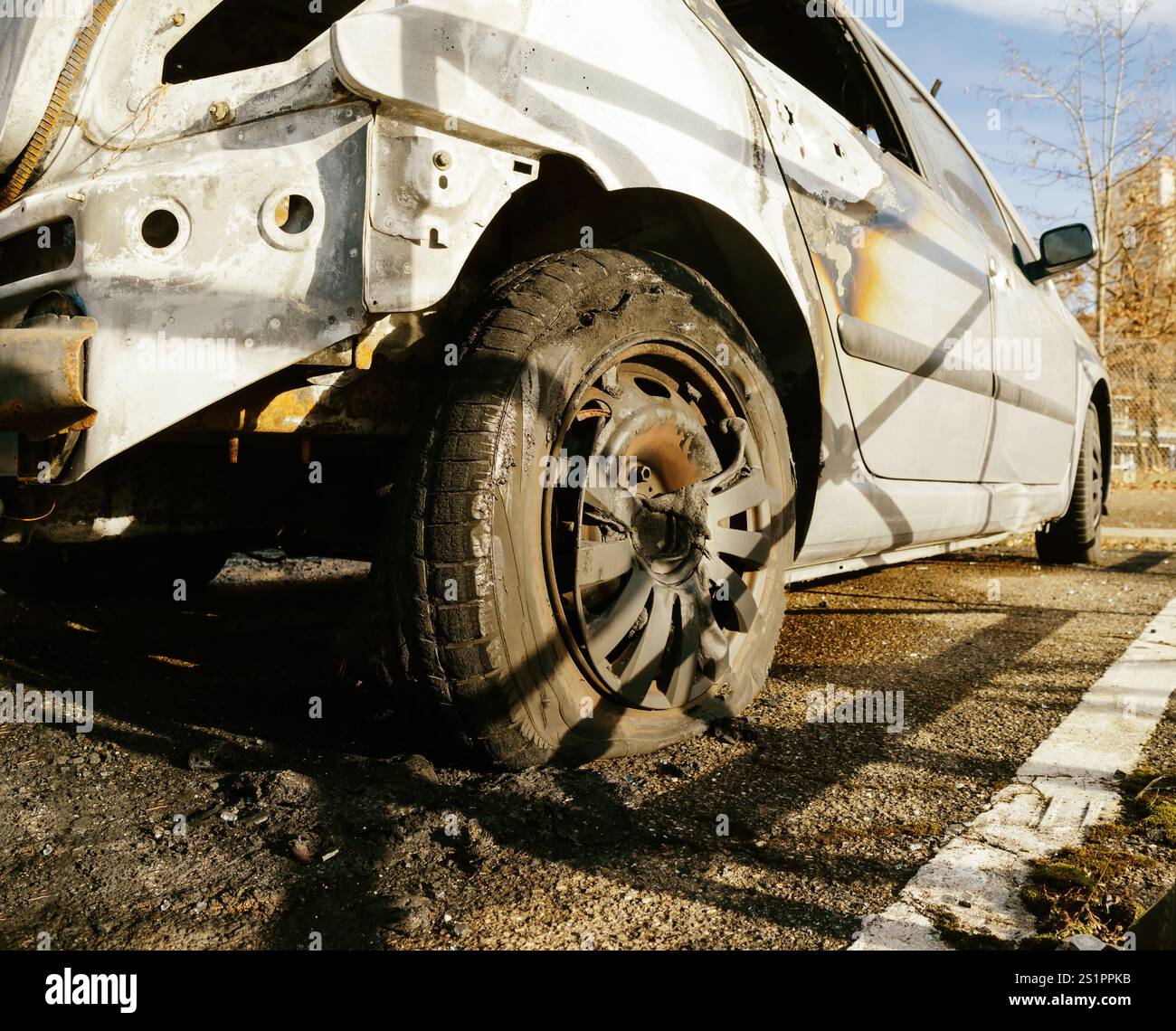 A burned-out car with visibly melted tires and fire damage to the body ...