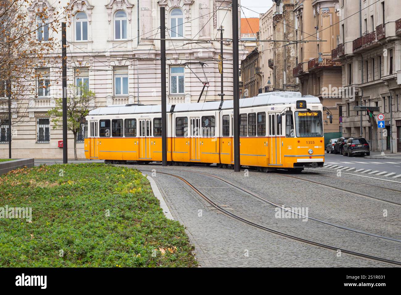 Traditional yellow orange colored tram rides on Kossuth Lajos square in ...