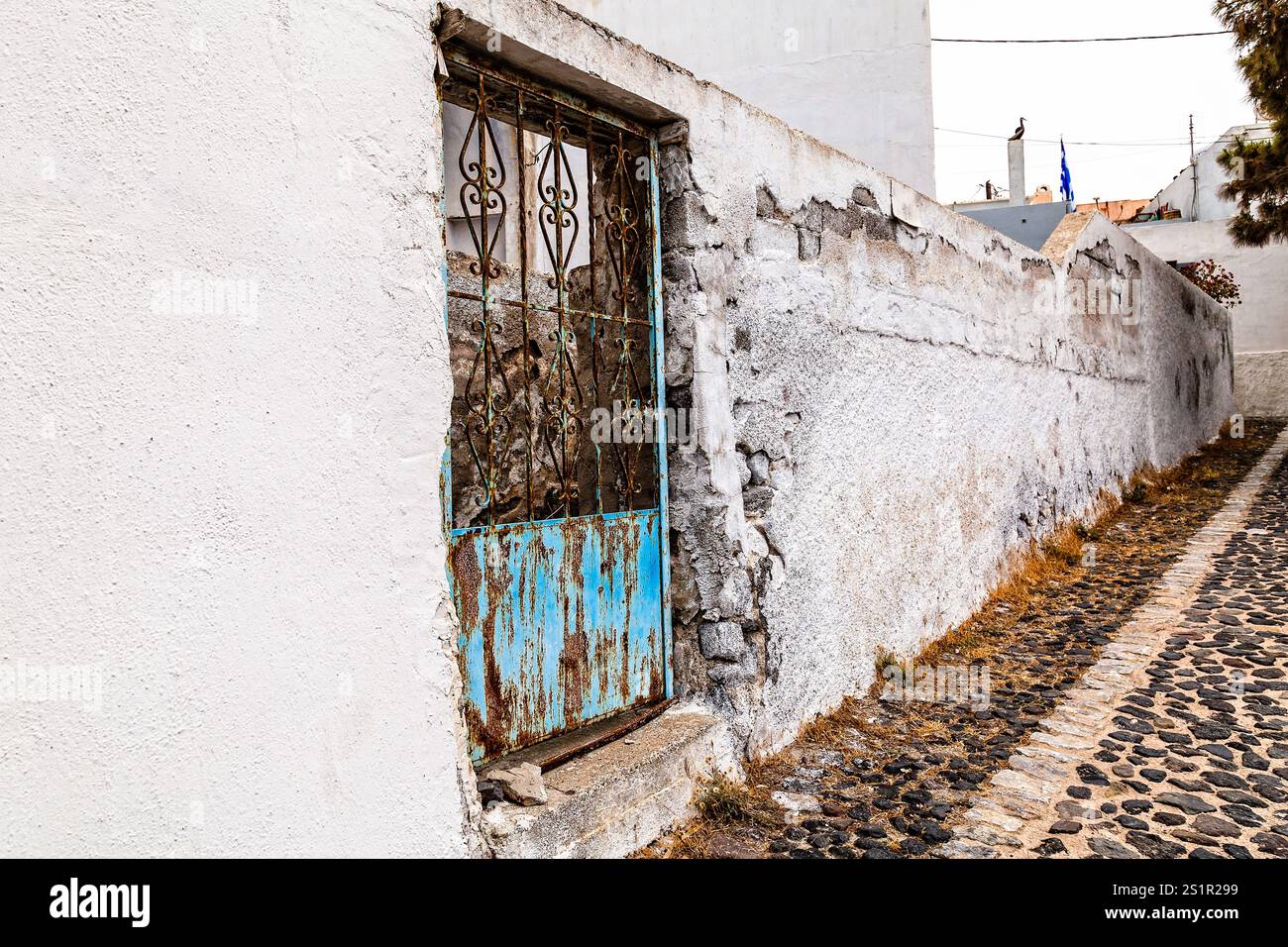 Aged Blue Metal Gate in a Weathered White Plaster Wall Along Cobbled ...