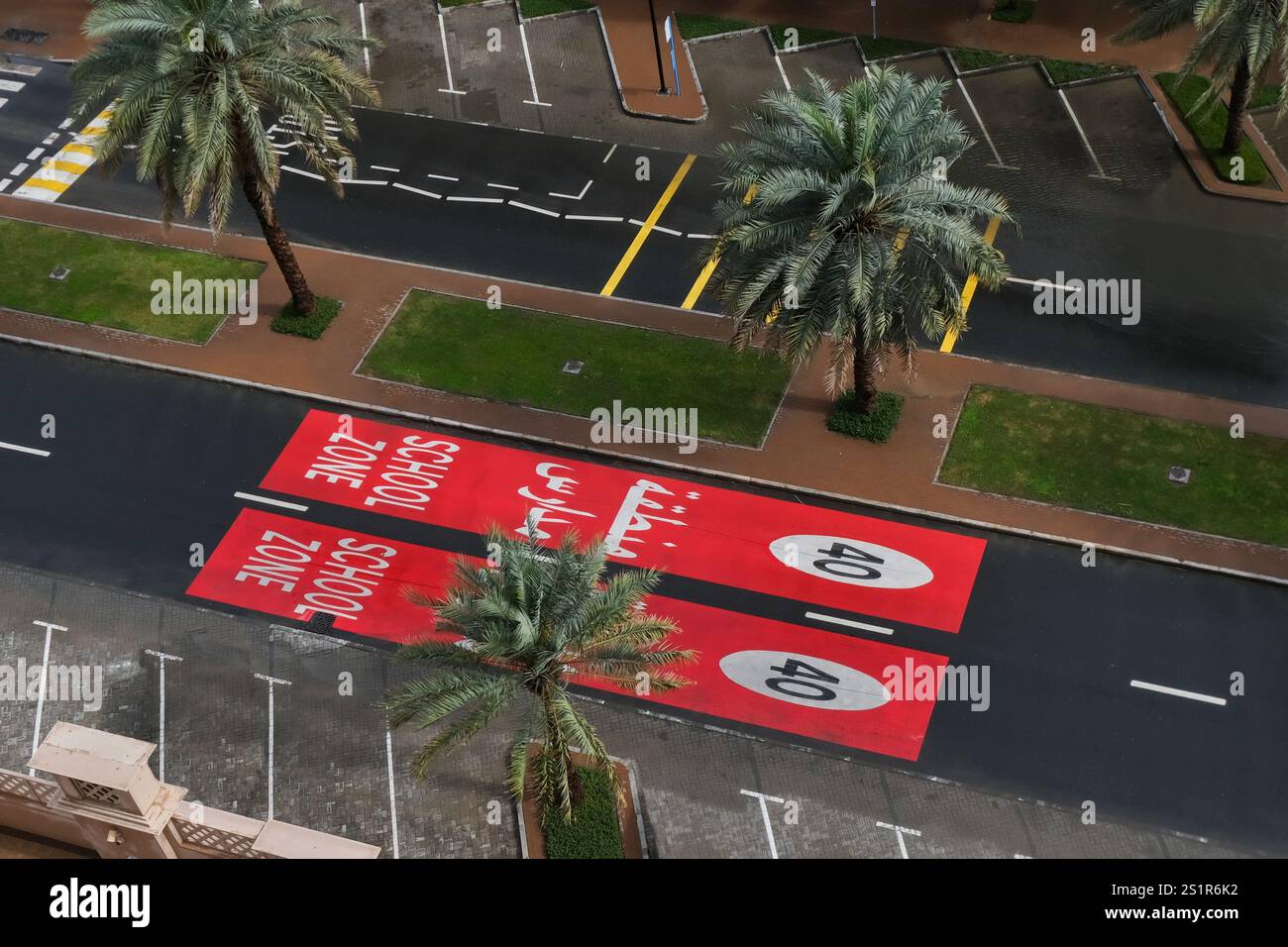 Red cautionary sign on asphalt at school zone in UAE, displaying speed ...