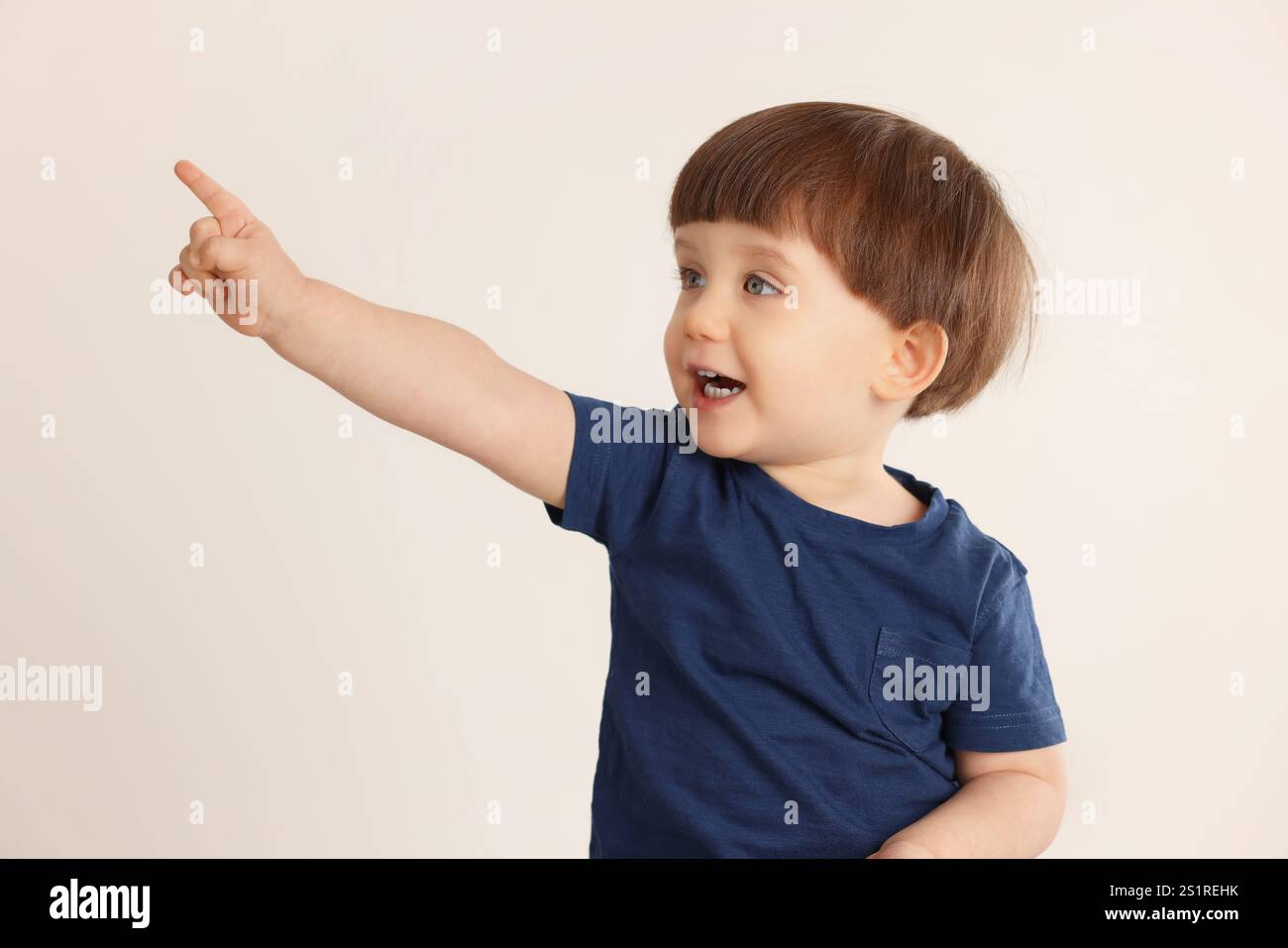 Cute little boy pointing at something on light grey background Stock ...