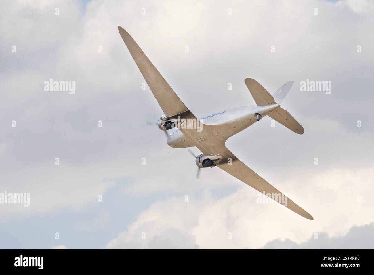Vintage twin engine propeller Li-2 airplane flying in the cloudy sky ...