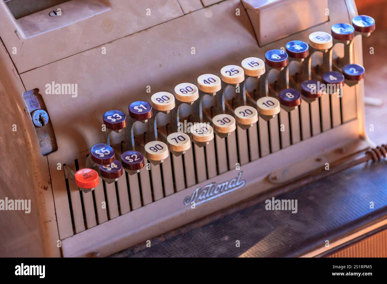 A vintage style cash register with a red button on the left side. The ...