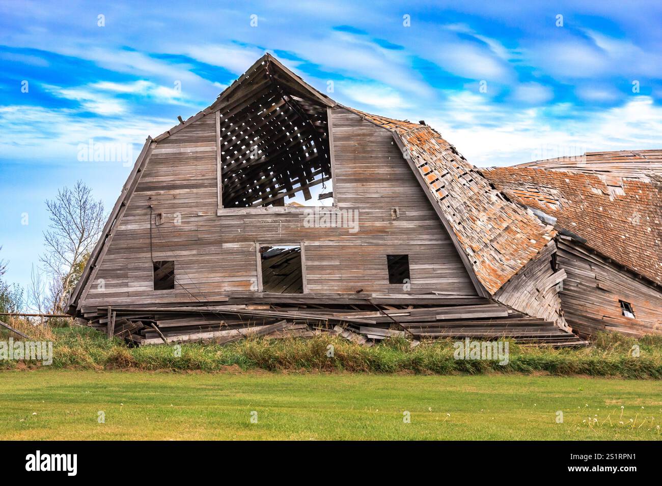A barn with a large open window and a roof that is missing a few ...