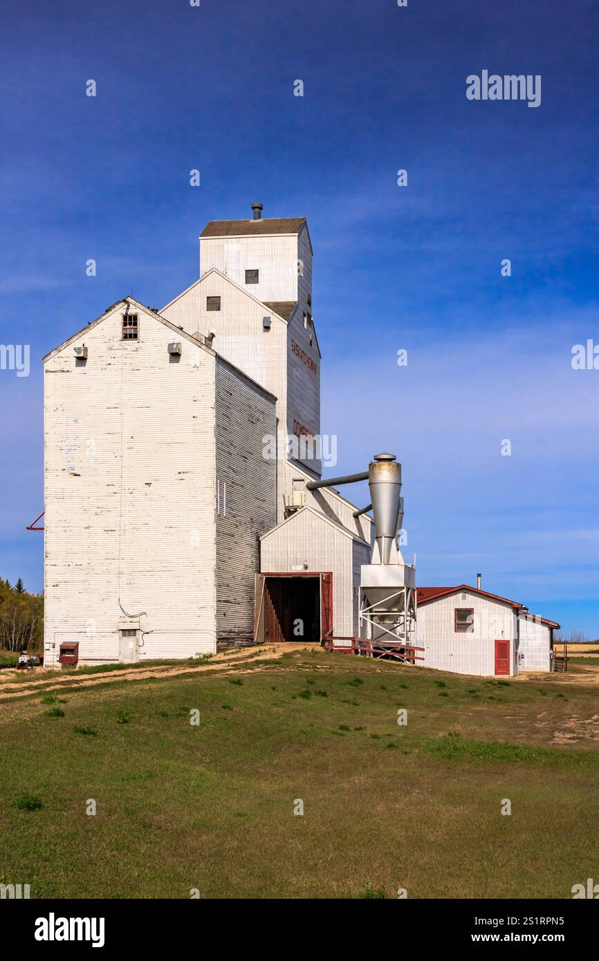 A large white grain silo with a red door sits on a hill. The silo is ...