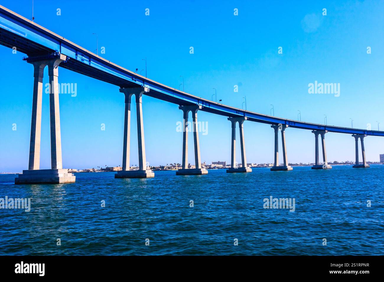 A long bridge spans a body of water. The bridge is blue and the water ...
