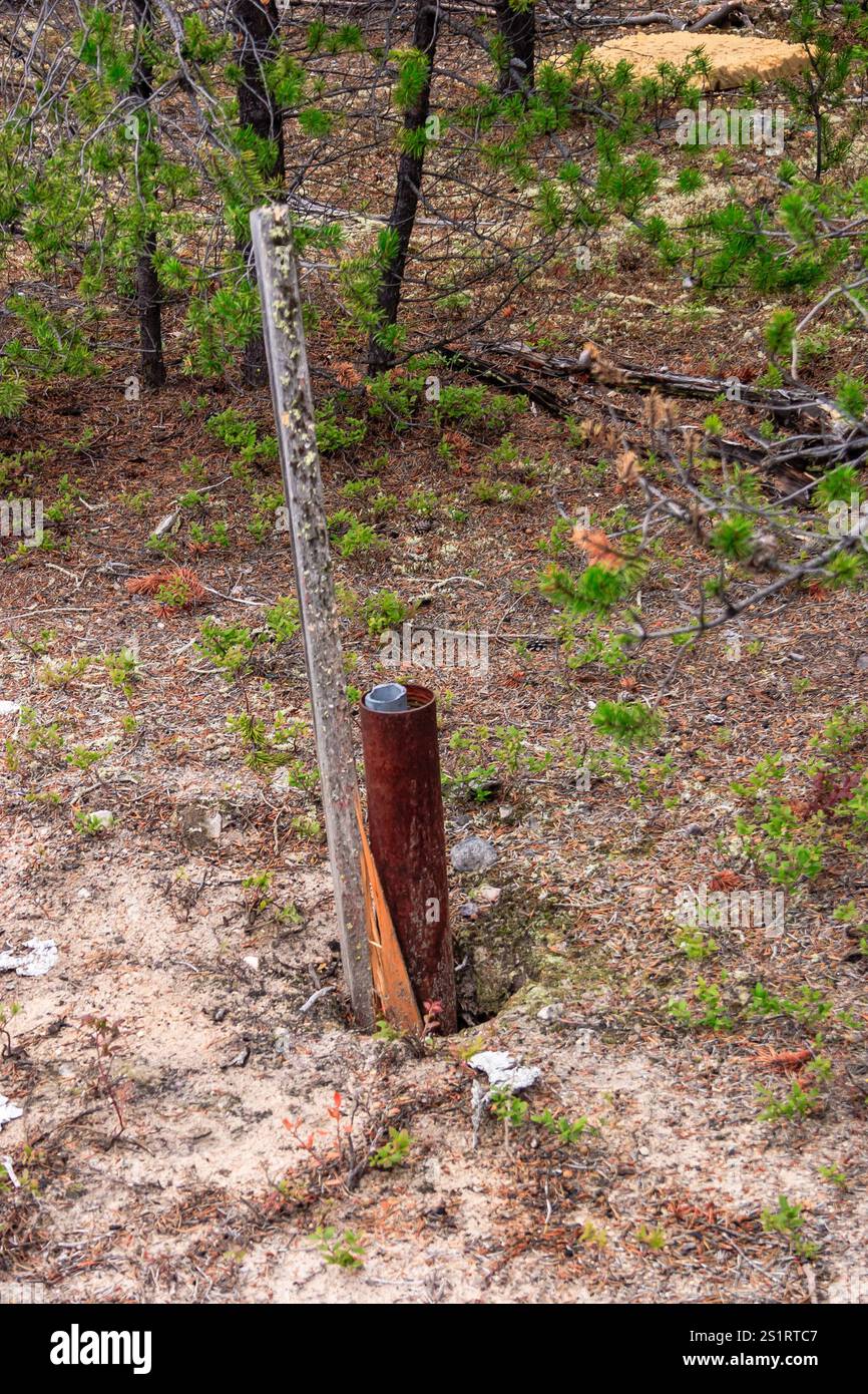 A rusty pipe sticking out of the ground in a field. The pipe is ...