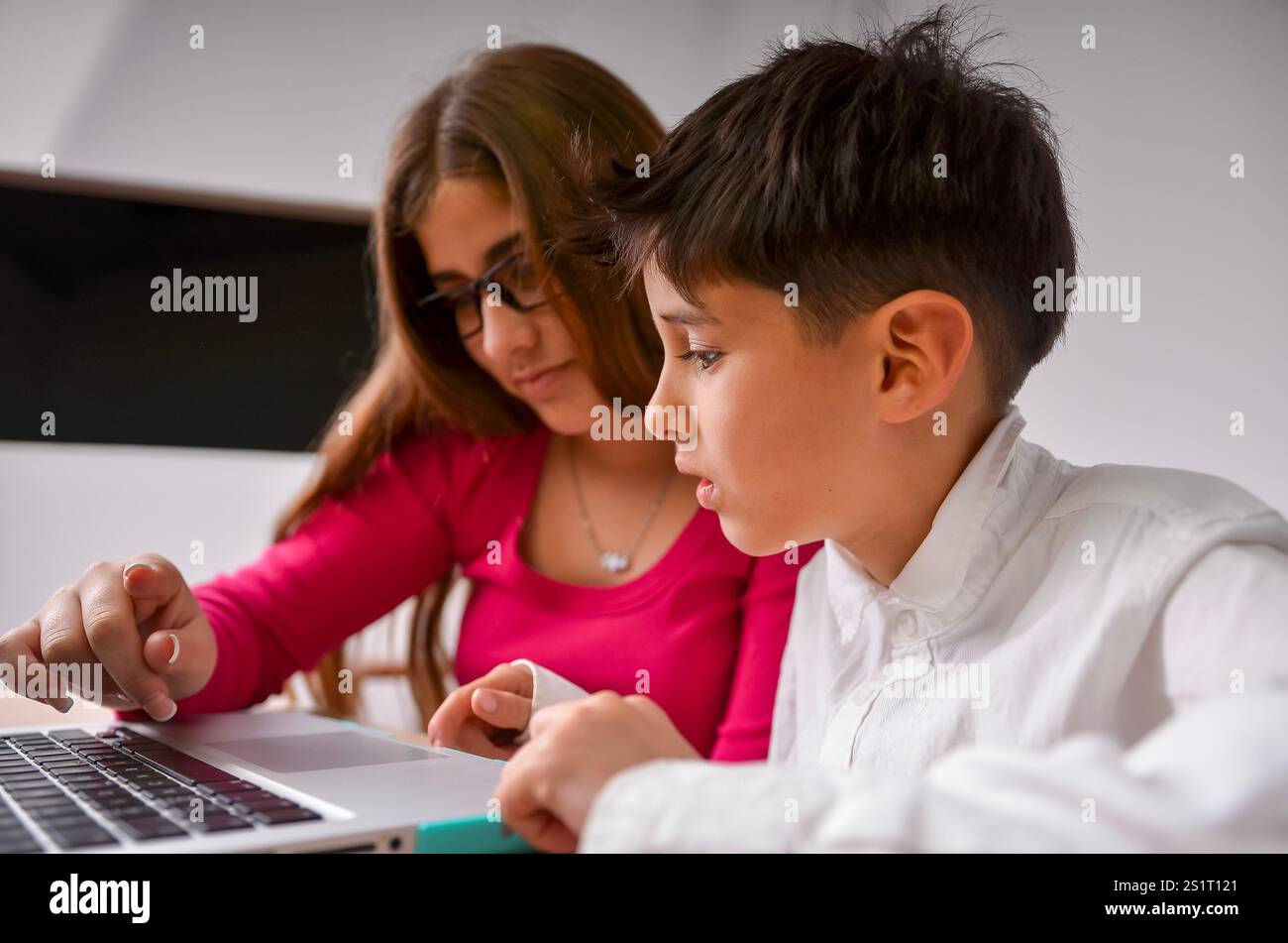 Young female teacher helping elementary school student with laptop ...