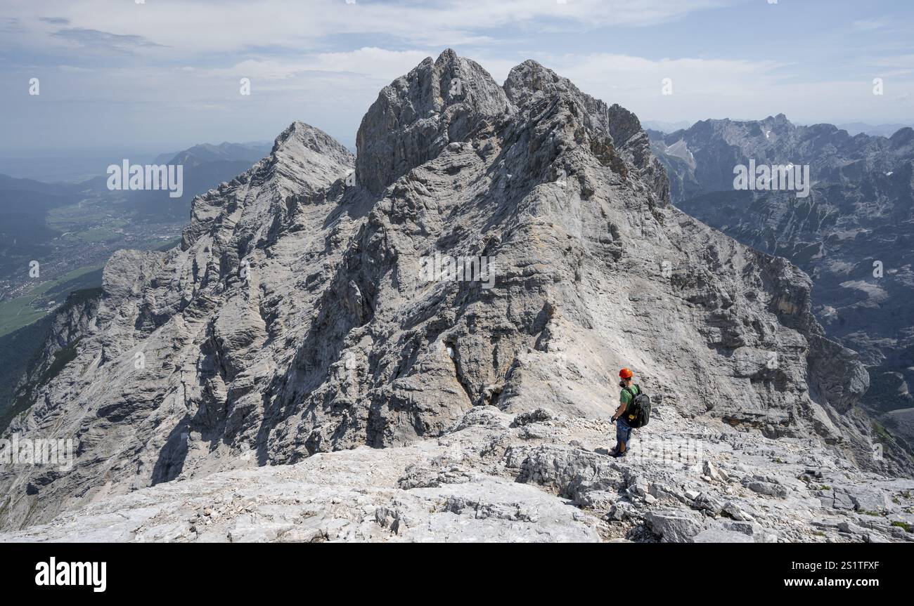 Mountaineer with helmet on a narrow rocky ridge, crossing the ...
