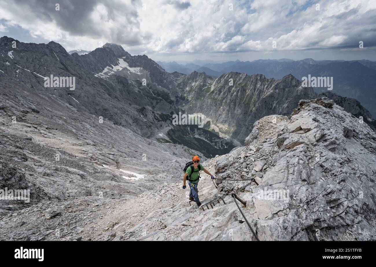 Mountaineer with helmet climbing on rock, on a narrow rocky ridge, view ...
