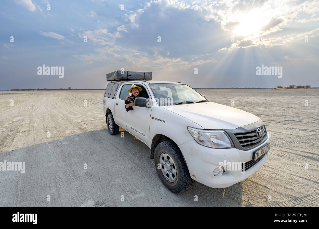 Young man with camera looking out the window of an off-road vehicle ...