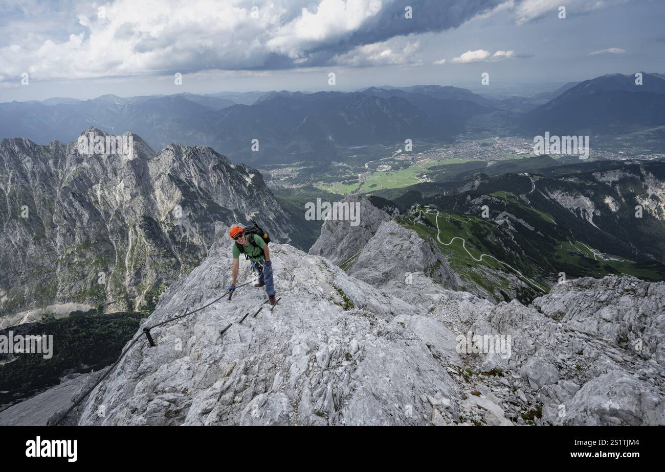 Mountaineer with helmet climbing on the rock in a secured climb, on a ...