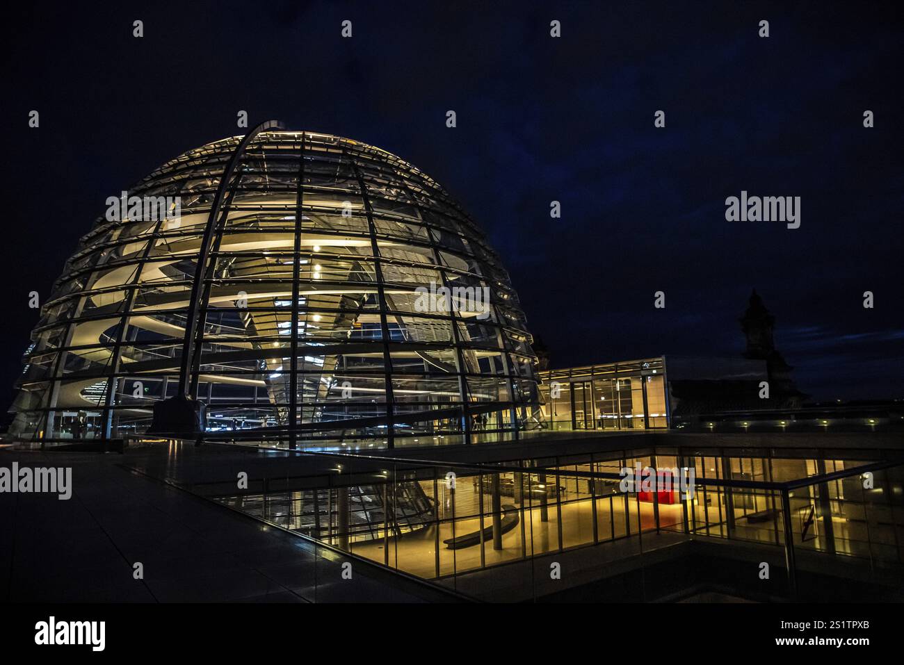 The illuminated glass dome of the Berlin Reichstag in the evening. The ...
