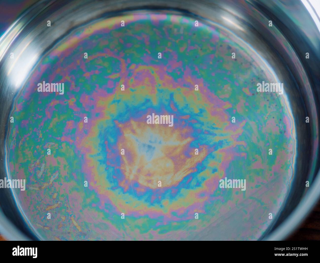 Iridescent color spots on the bottom of a stainless steel pan. Light ...