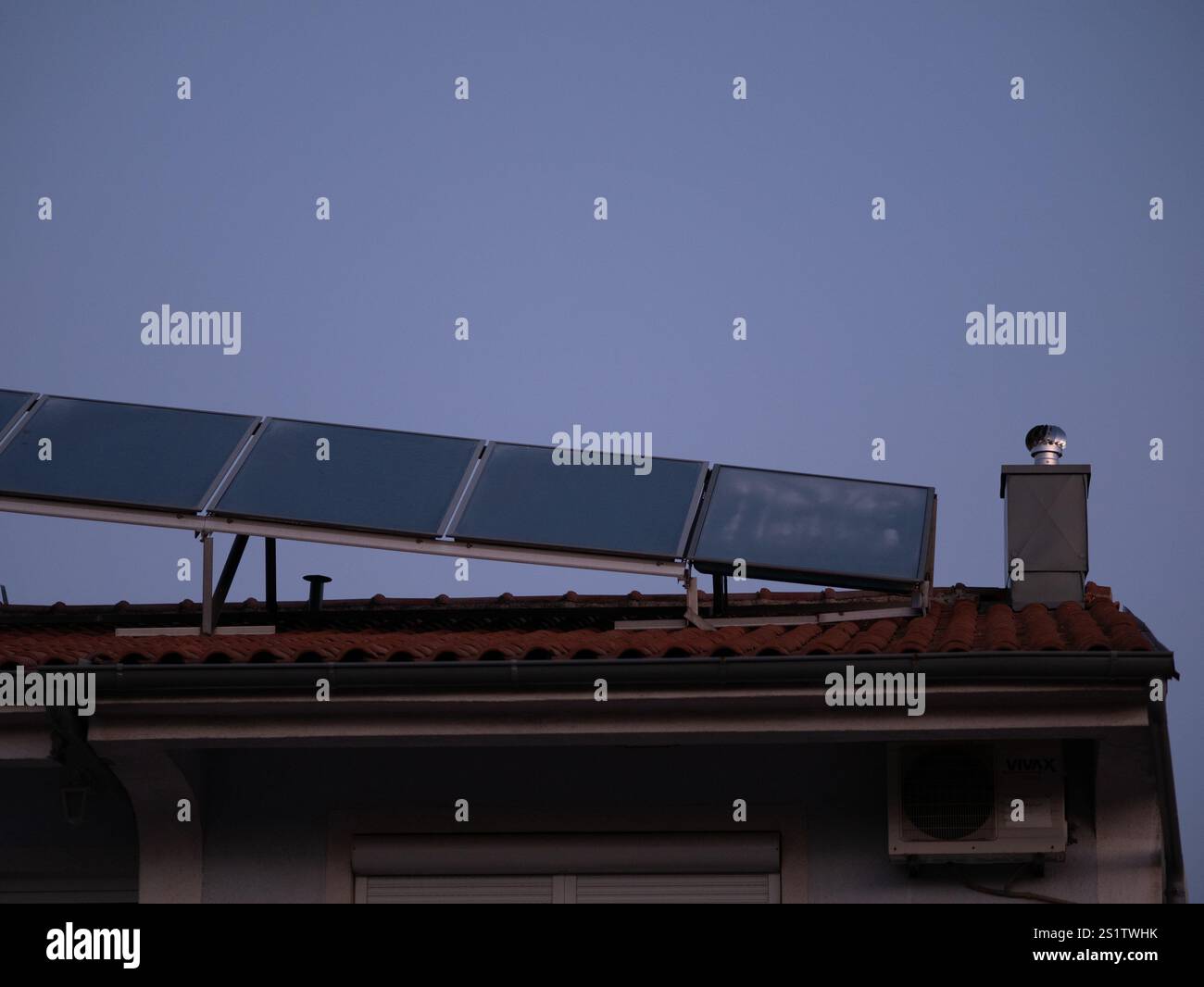 Solar panels installed above the tiled roof. Ventilation pipe with ...