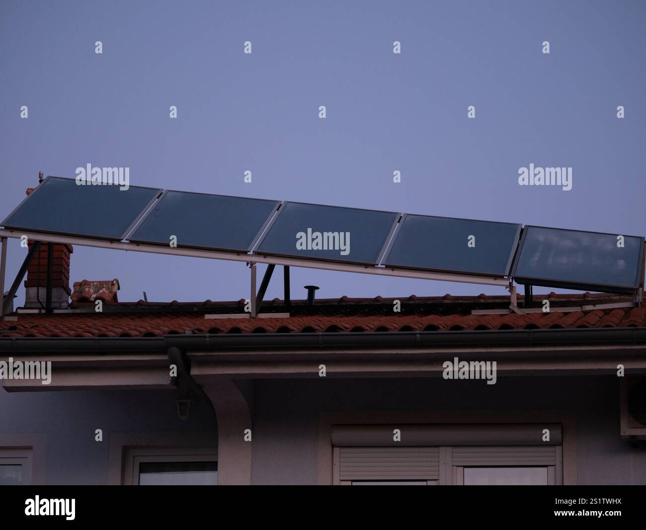 Solar panels installed above the tiled roof. Ventilation pipe with ...