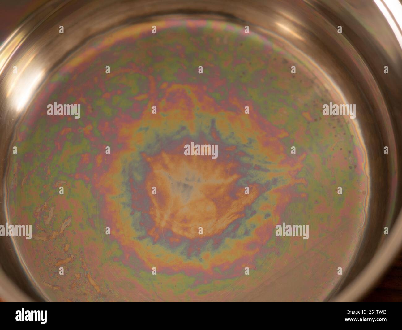 Iridescent color spots on the bottom of a stainless steel pan. Light ...