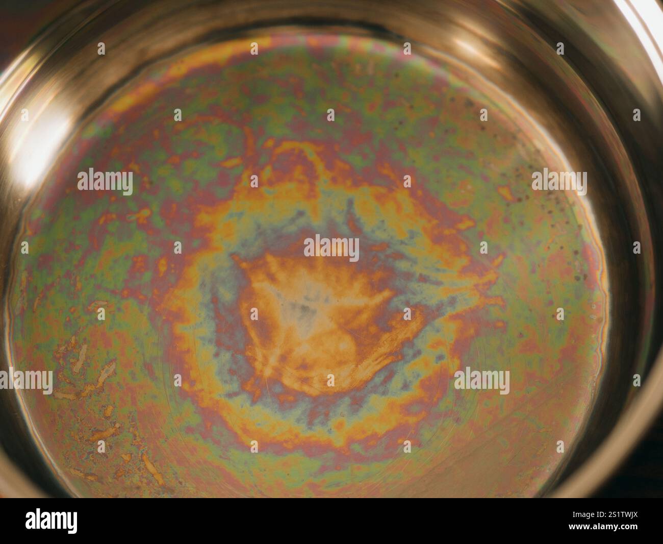 Iridescent color spots on the bottom of a stainless steel pan. Light ...