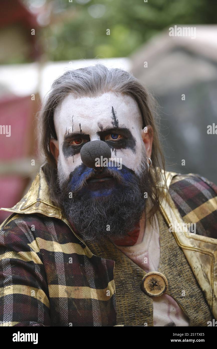 A menacing-looking clown with a beard and eye-catching costume outdoors ...